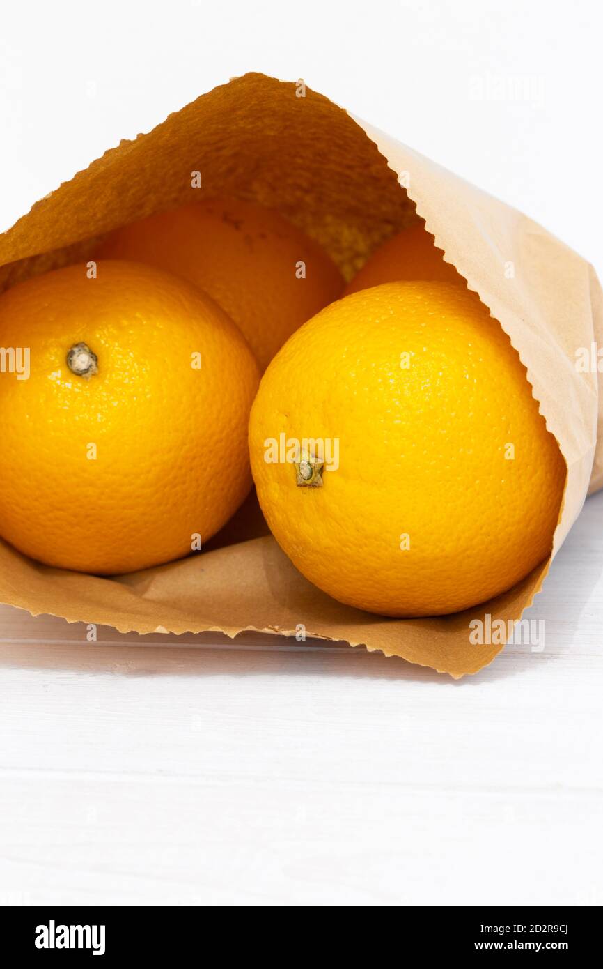 Oranges in a brown paper bag on a white wood background ...