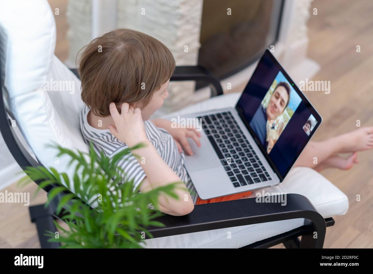 Happy kid boy sit on chair with computer using laptop having a video ...