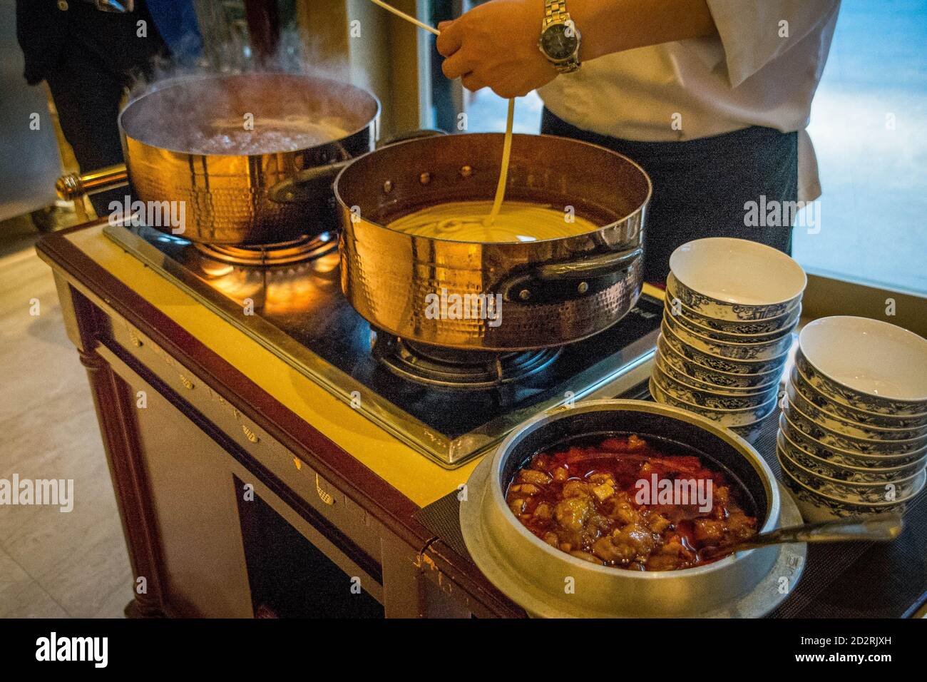 a chinese chef cooking chinese noodles at a live cooking station Stock ...