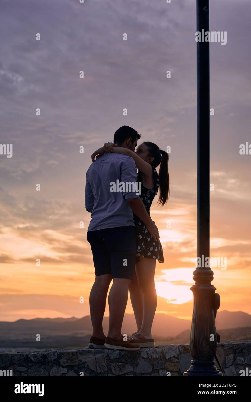 Side view low angle of tender couple in love standing on stone border ...