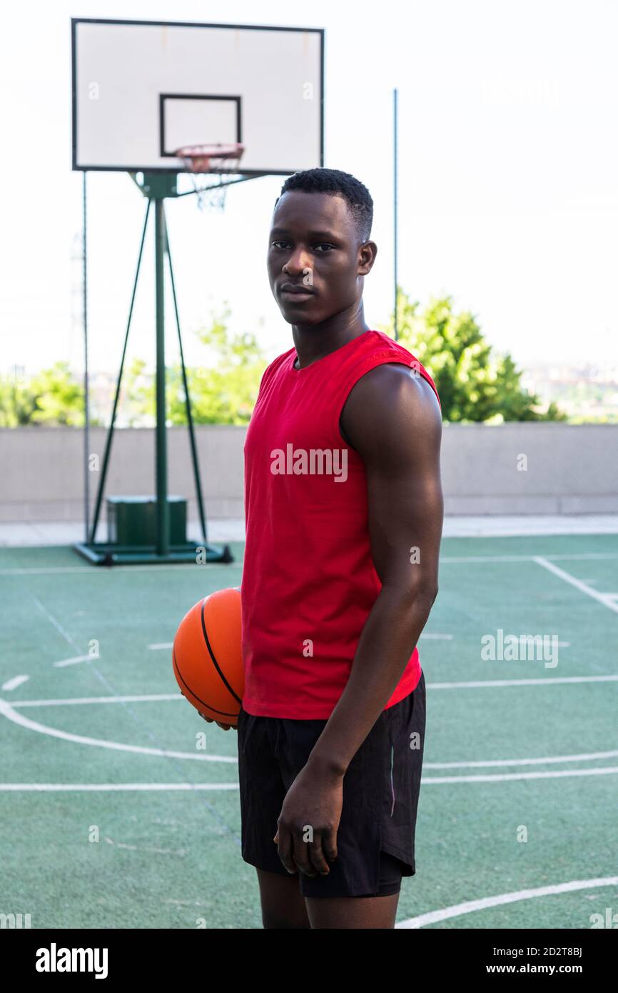 Determined male basketball player standing with ball on playground in ...