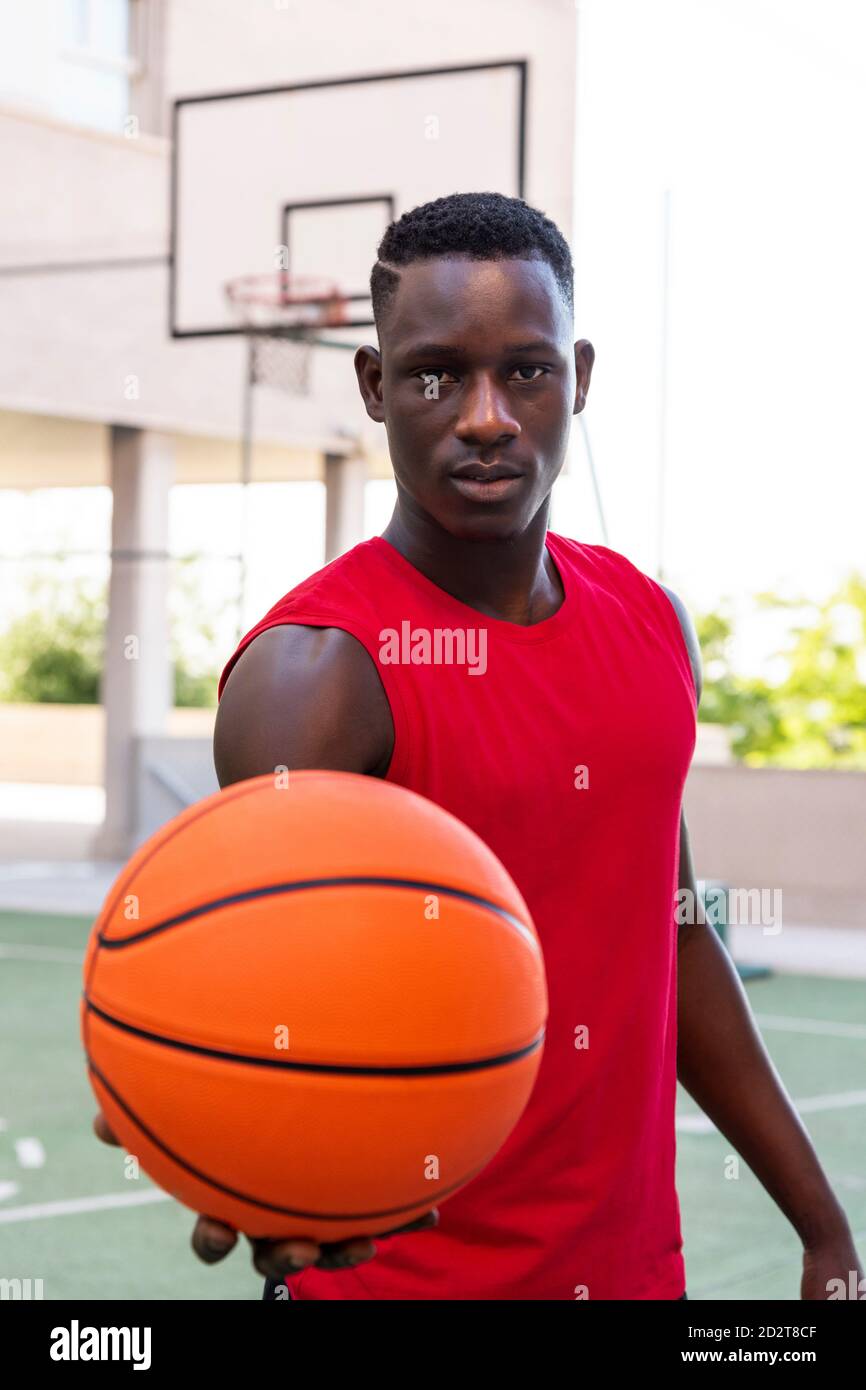 Determined male basketball player standing with ball on playground in ...
