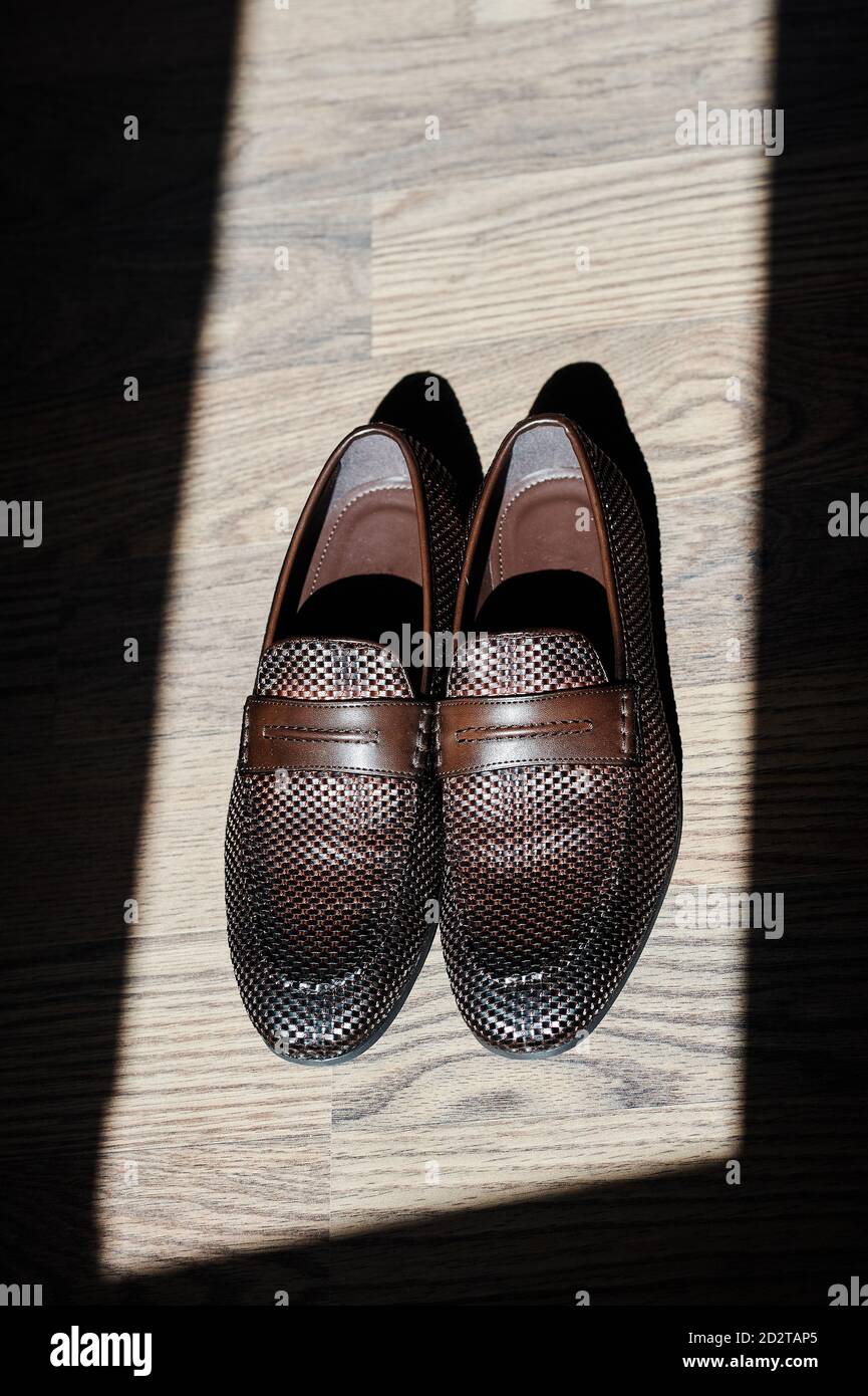 Pair of leather loafers placed on wooden floor illuminated by sunlight ...