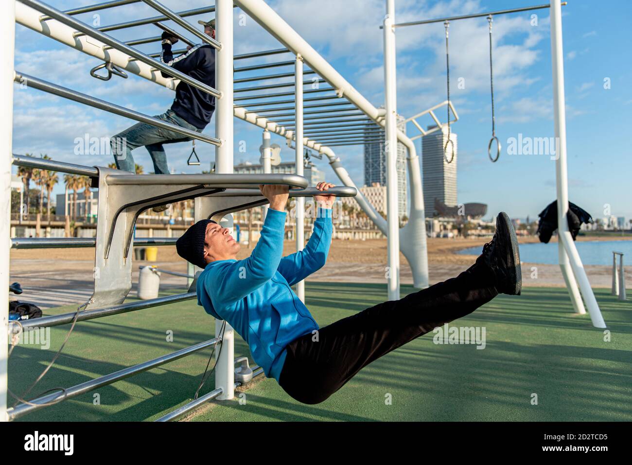 Side view of focused athletic male in activewear performing hanging leg ...