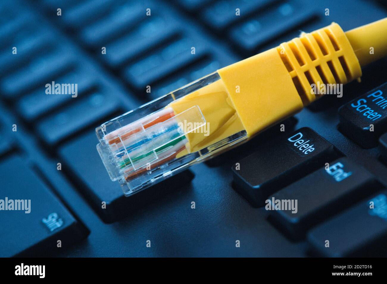 Yellow internet cable on computer keyboard with shallow depth of field ...