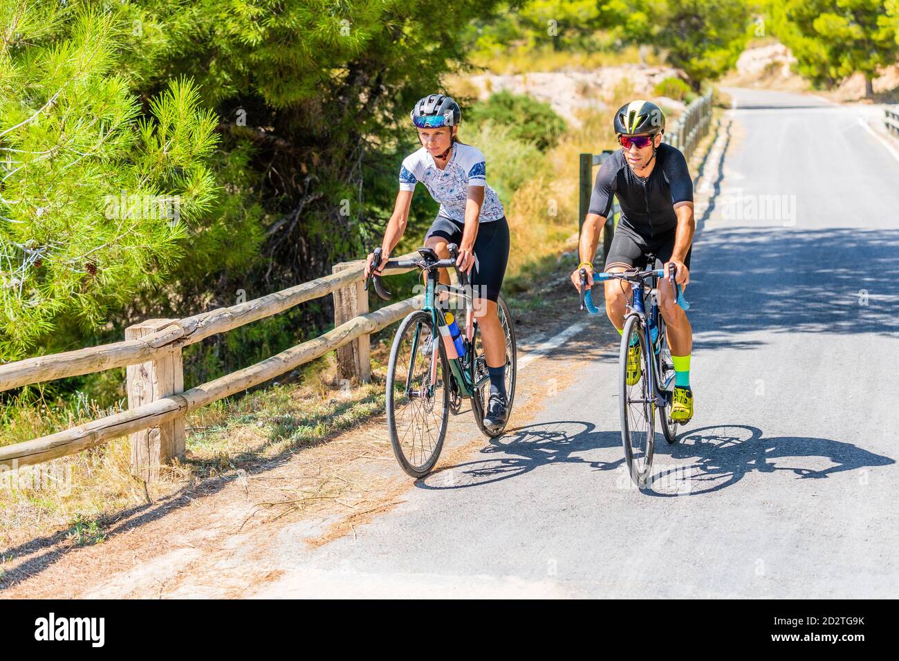 Full length of bicyclists in sportswear and helmets cycling together on ...