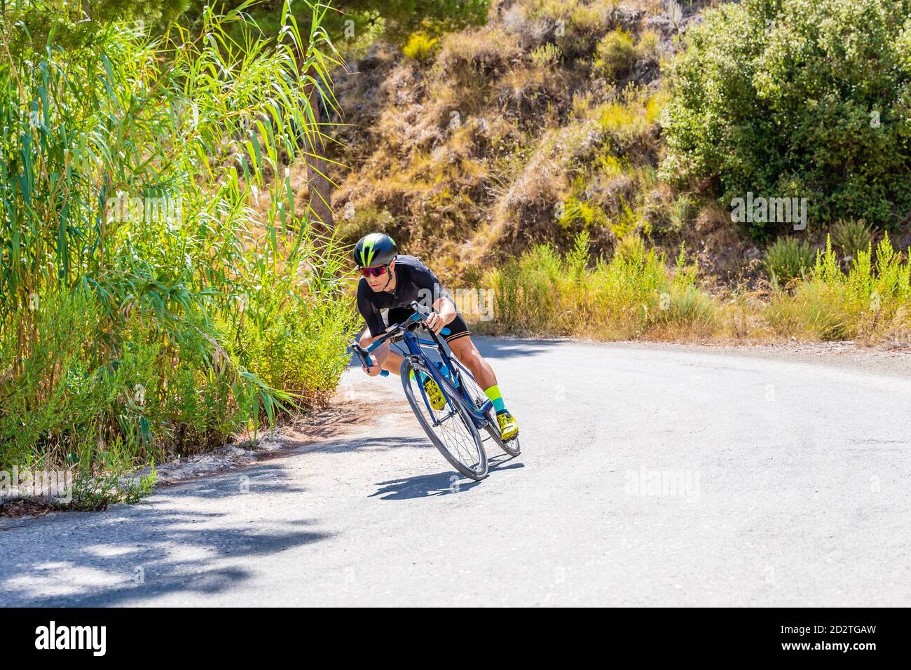 Full length of strong male bicyclist riding bike on curvy paved road ...