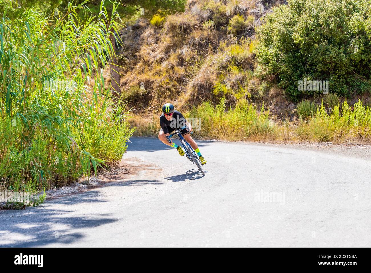 Full length of strong male bicyclist riding bike on curvy paved road ...