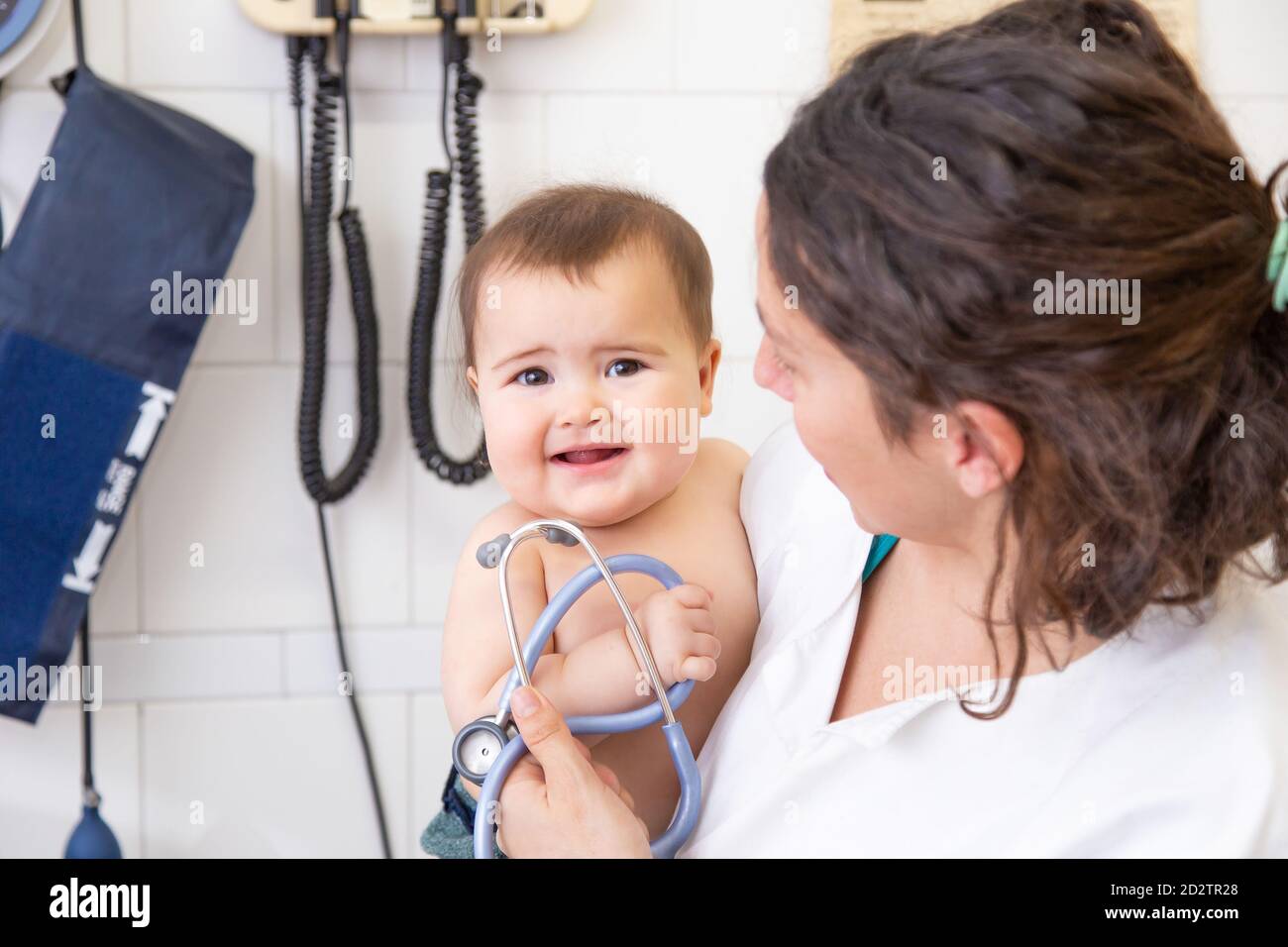 Little beautiful baby having a medical examination by a Woman ...
