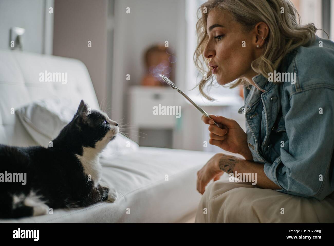 Side view of enchantress conjuring with magic wand while looking at cat ...