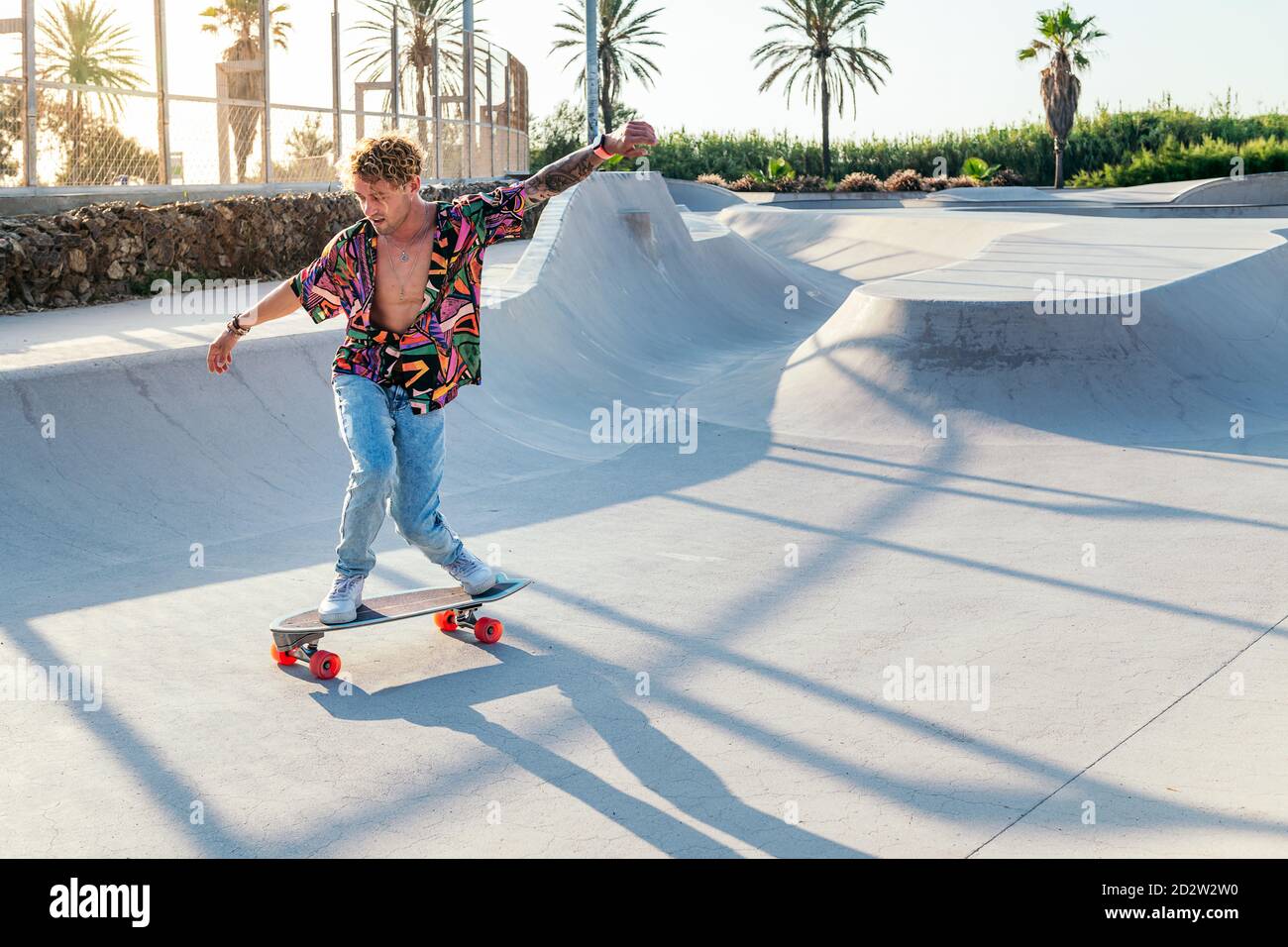Full body of funky young male skateboarder in trendy colorful shirt and ...