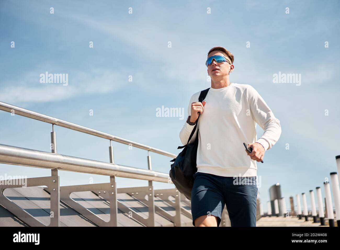 From below full body of confident young male in trendy casual outfit ...
