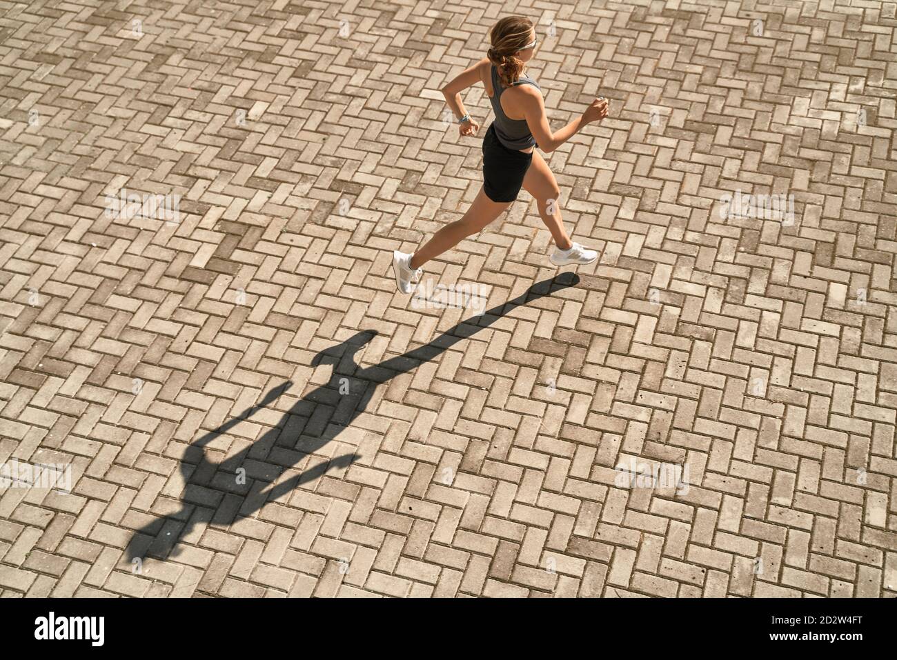 From above full body of active slim female in sportswear running fast ...