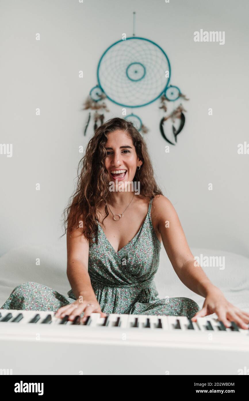 Talented ethnic female musician playing piano while sitting in modern ...