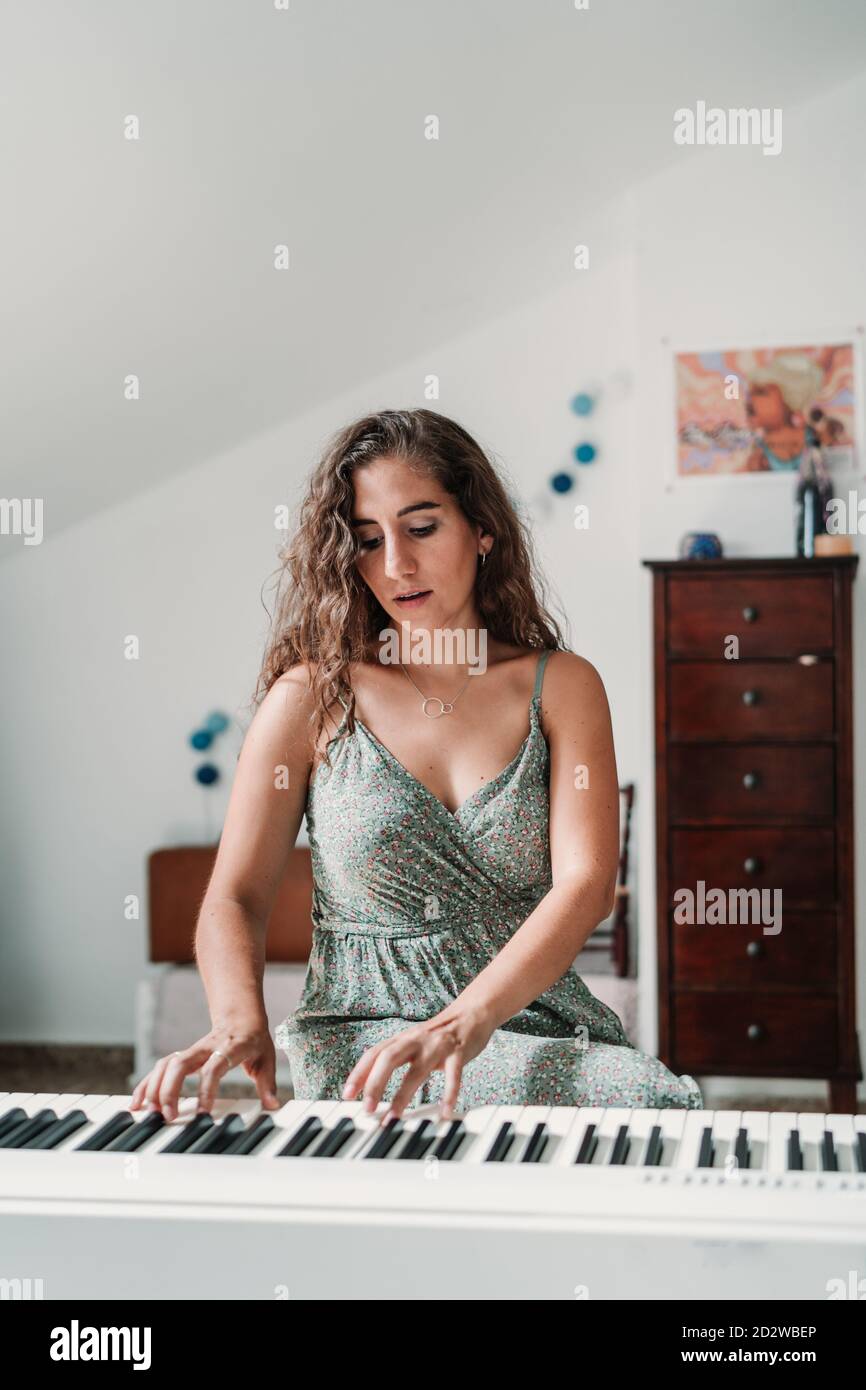 Talented ethnic female musician playing piano while sitting in modern ...