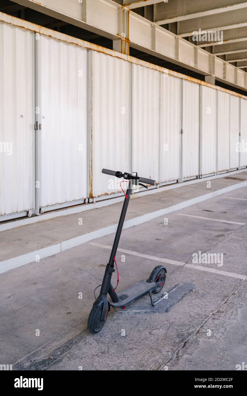 Modern electric scooter placed on paved parking lot against metal wall ...