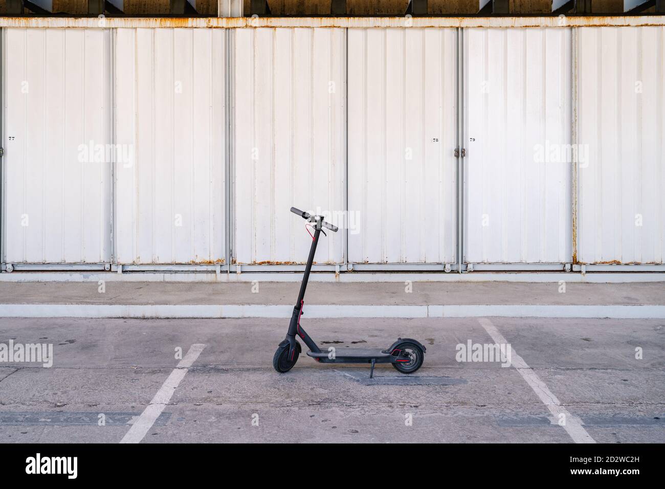 Modern electric scooter placed on paved parking lot against metal wall ...