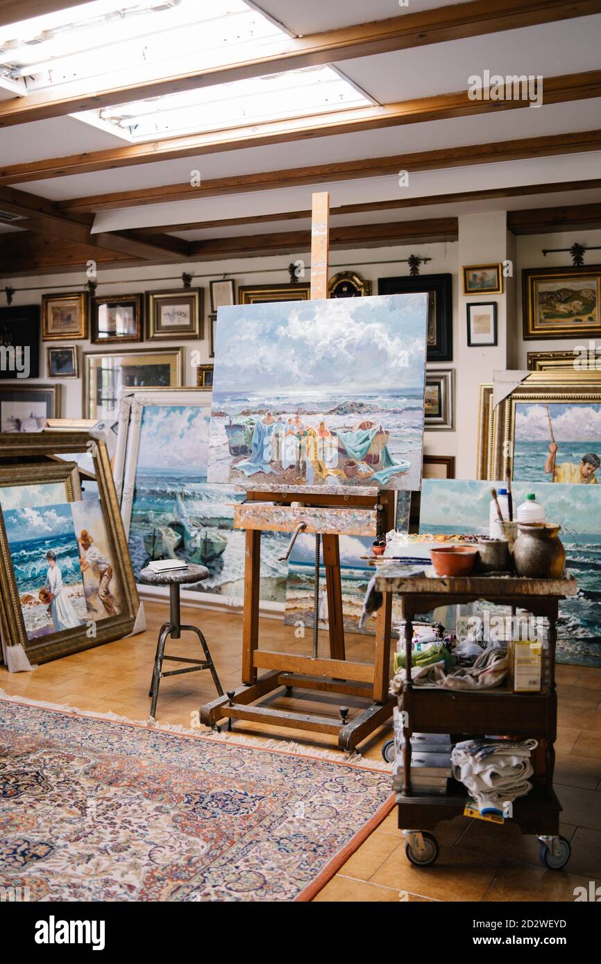 Interior of creative art workshop with painting on easel near shelf ...