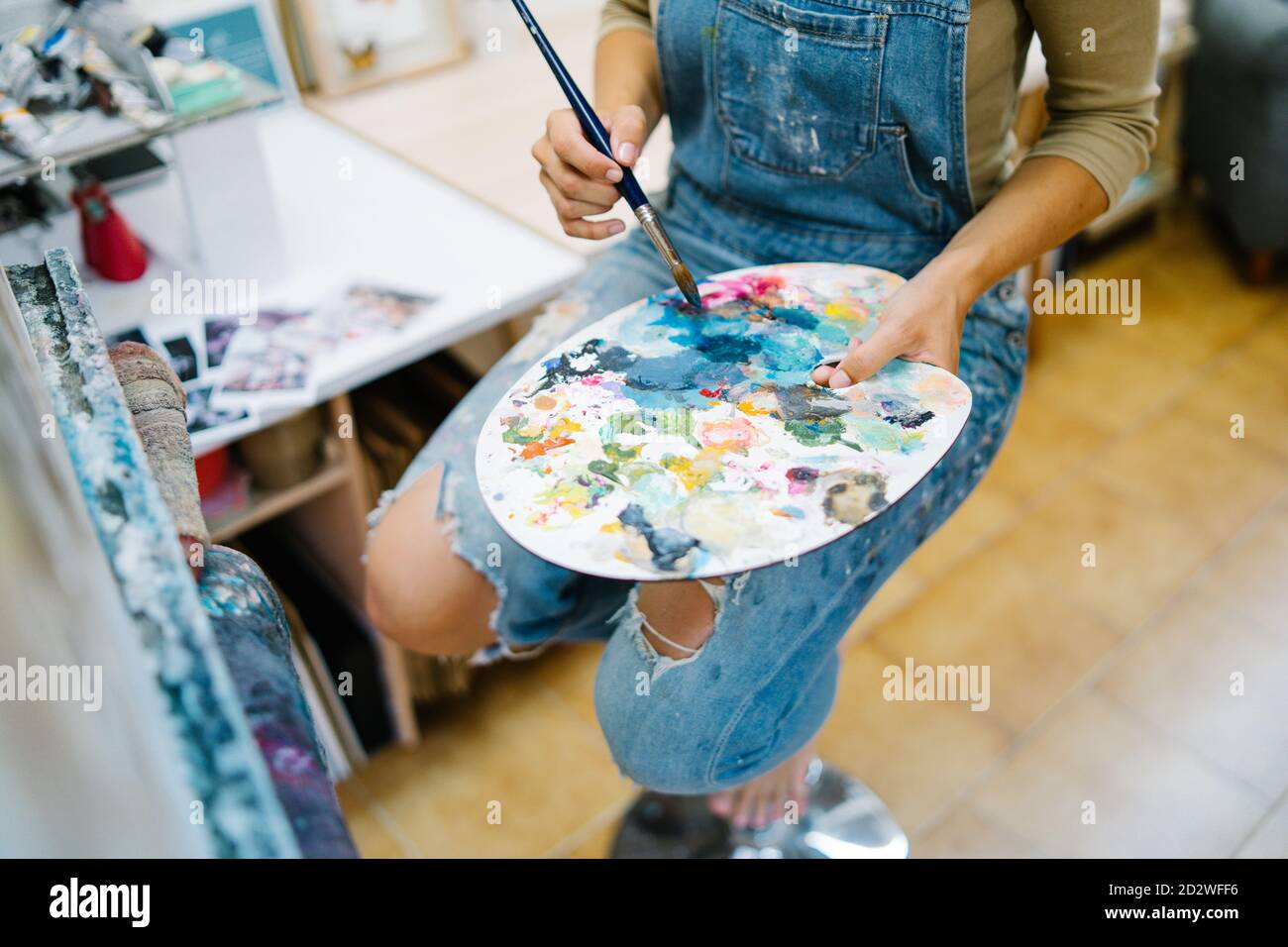 Crop anonymous artist taking paint from colorful art palette while ...