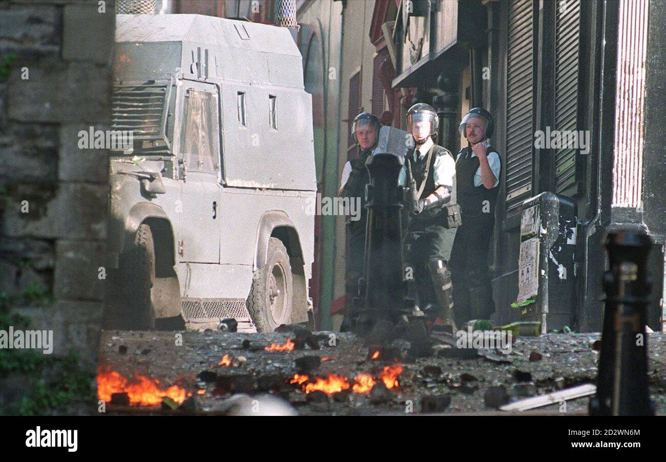 An RUC officer prepares to fire a baton round at rioters in the walled ...