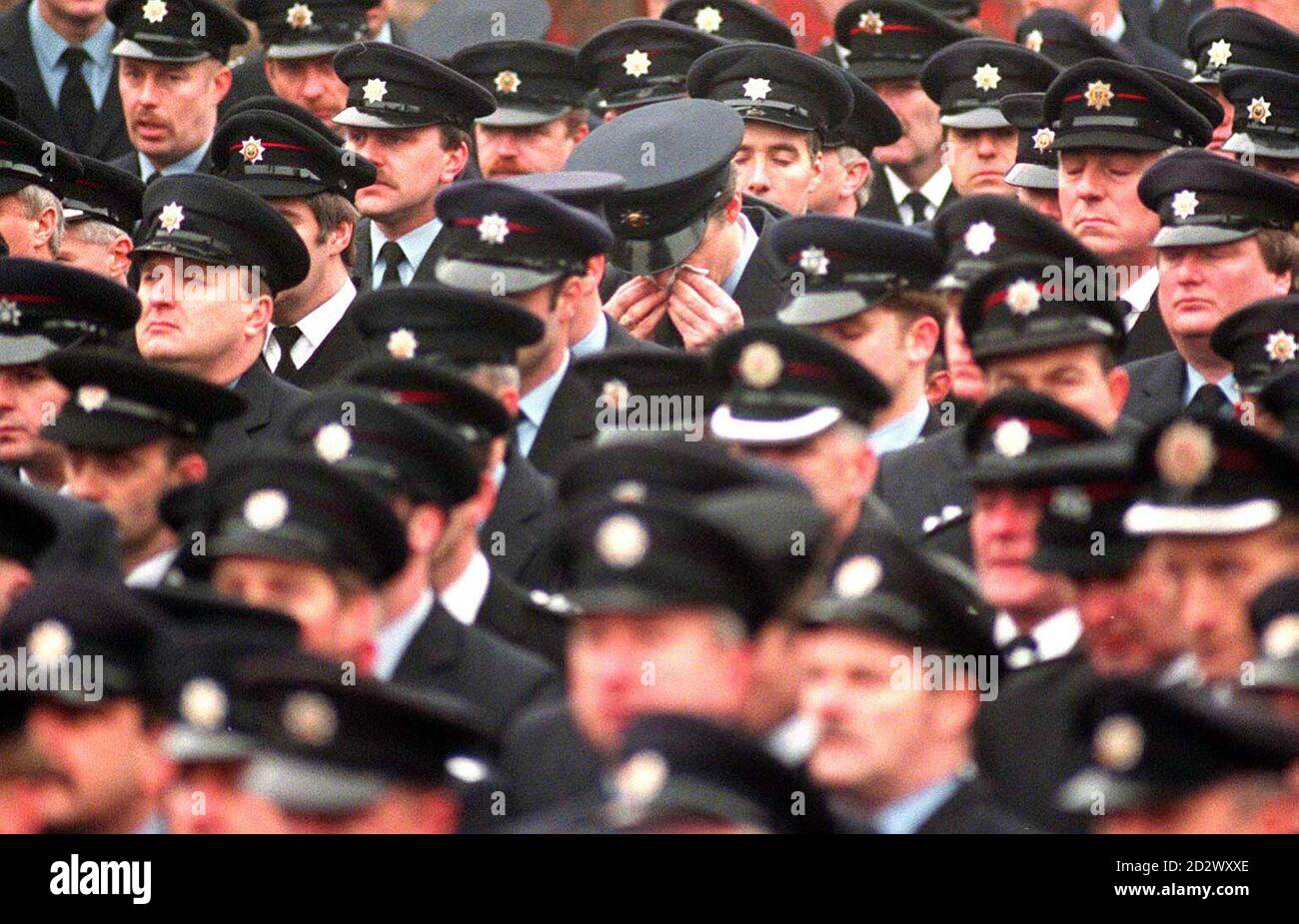 A grieving fireman bows his head as he stands among his colleagues at ...