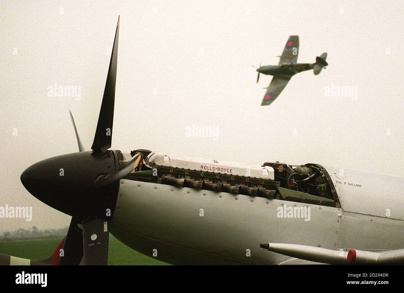 A lone Spitfire flys past a Spitfire on the ground during a press ...