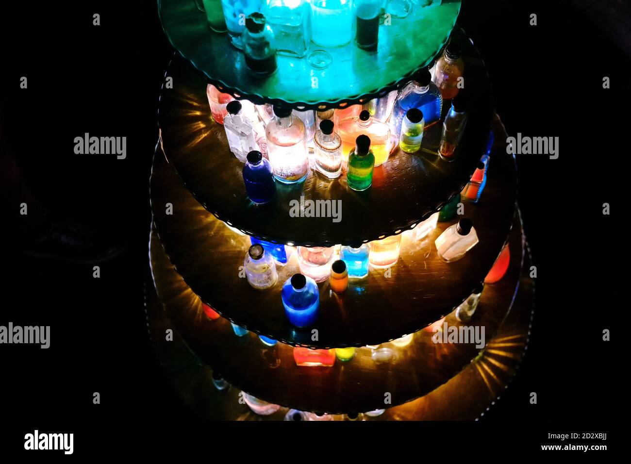 Glowing vials and bottles of liquid on a round stand in the dark Stock ...