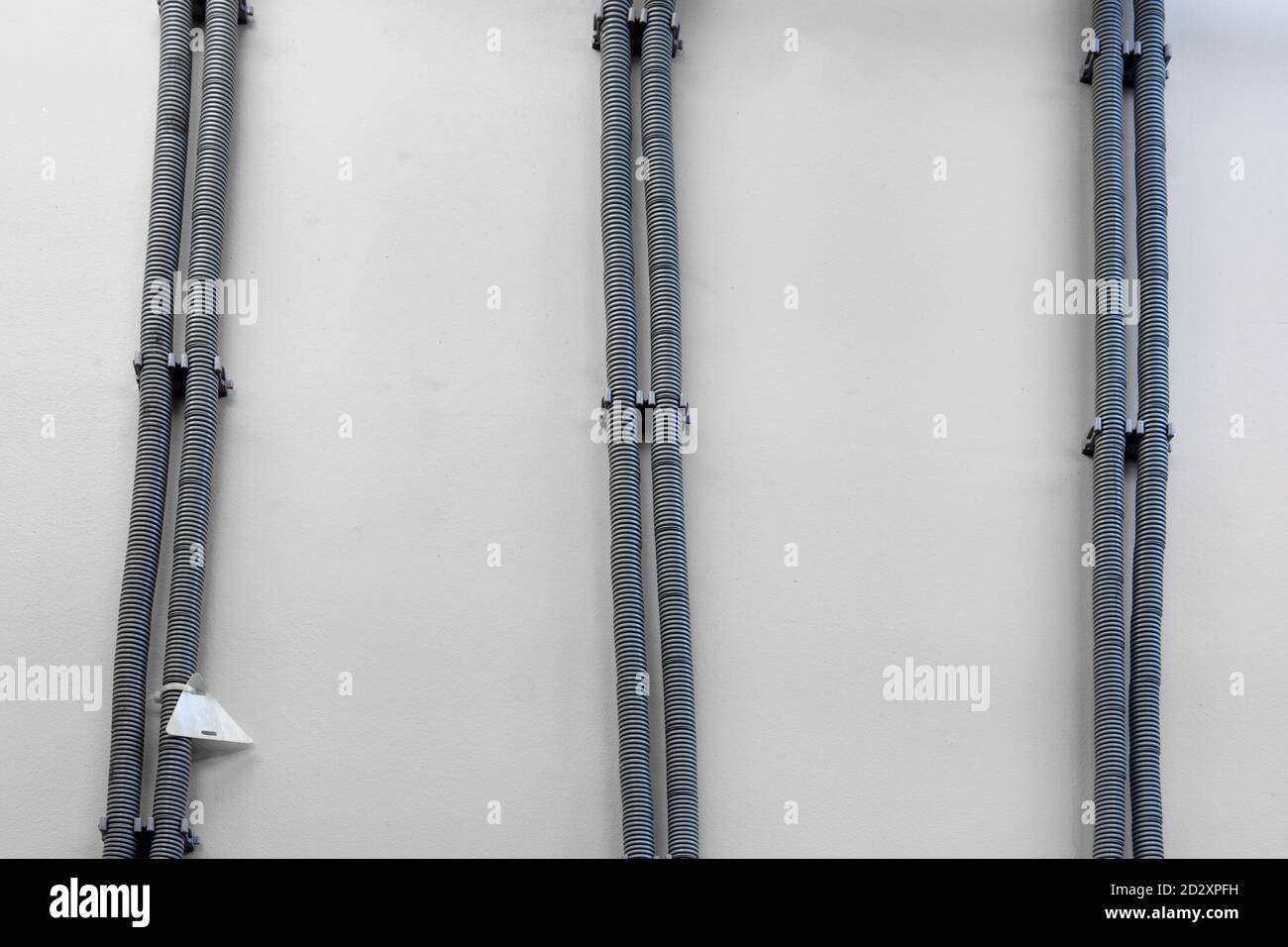 Wires on the wall in a protective round metal casing. Corrugated grey ...