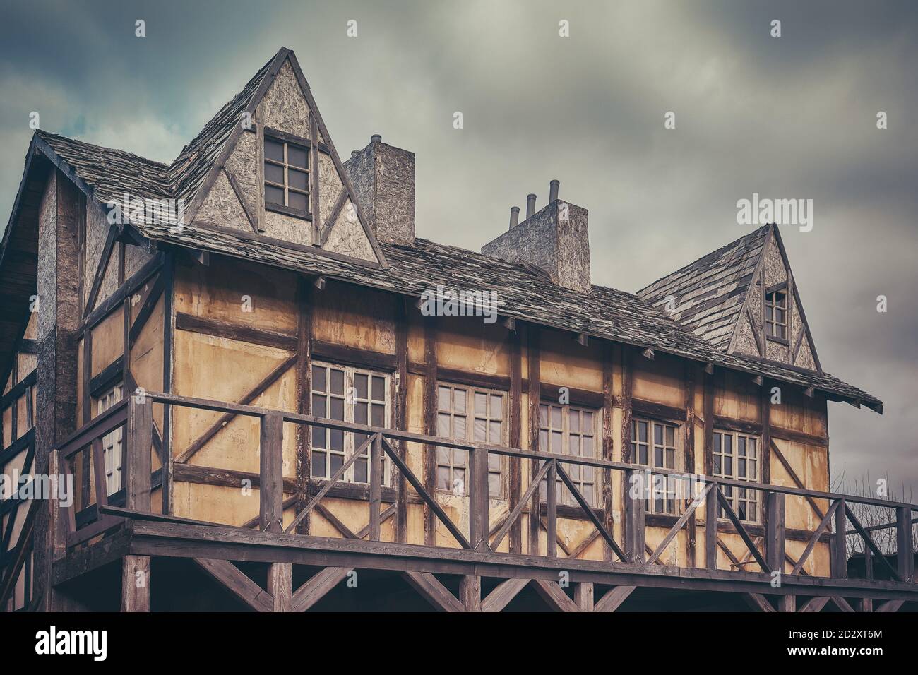 Retro house with attic and wooden balcony against dark gloomy sky ...