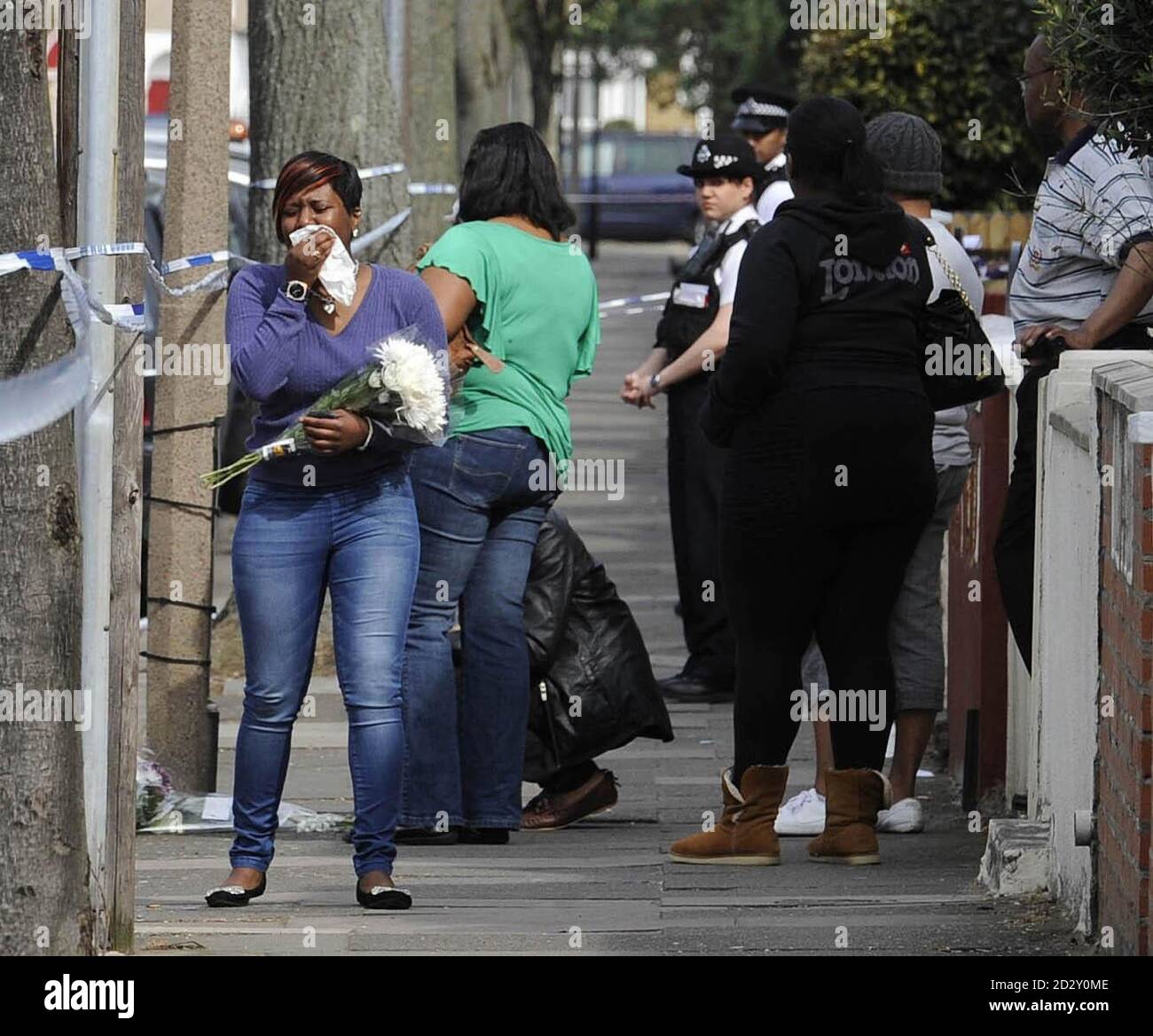 A relative waits to lay flowers at the scene in Edmonton, north London ...