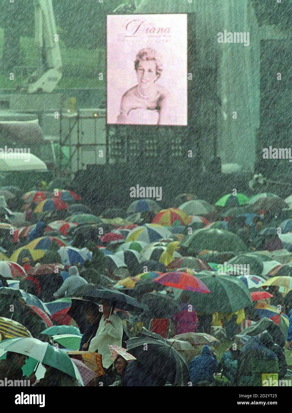 Crowds huddle under umbrellas to escape the driving rain before last ...