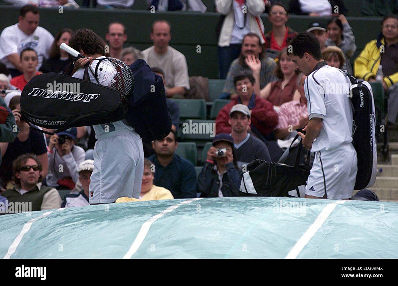 Cedric Pioline (left) and Tim Henman leave Court One after rain stopped ...