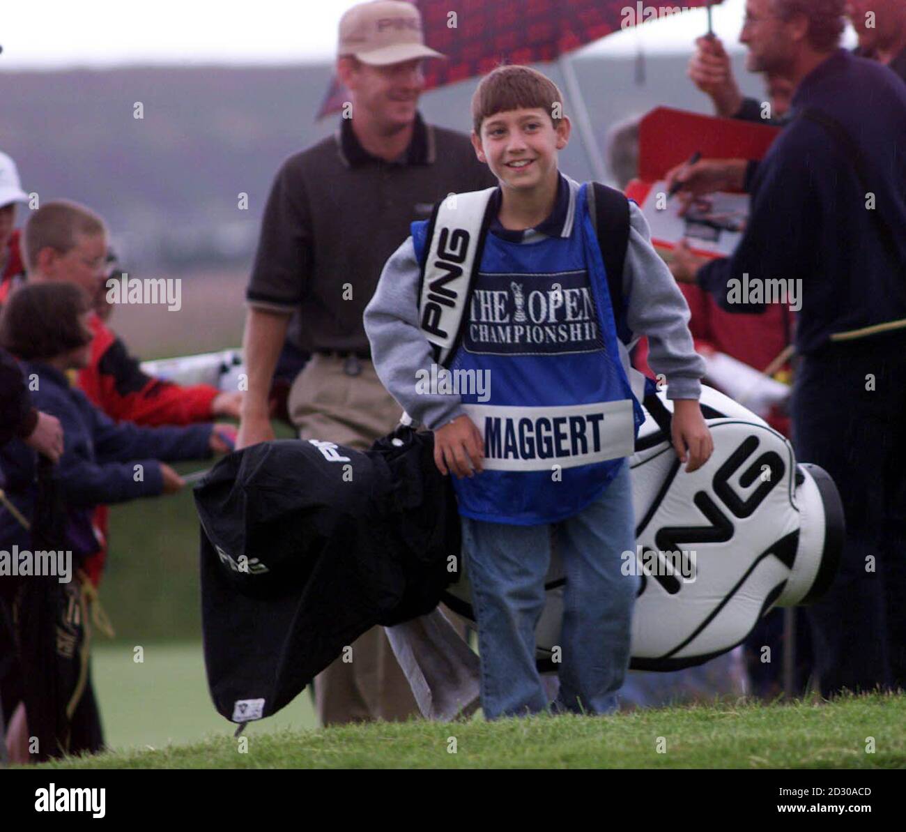 American Matt Maggert, aged 10, carries his father Jeff's golf bag ...