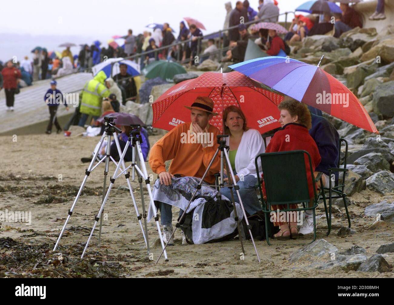 Crowds on the beach wait for the rain clouds to disappear, before the ...