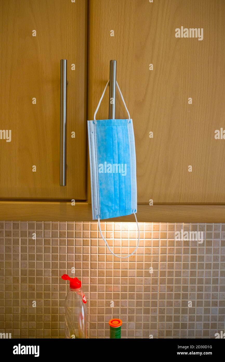 new surgical face mask hanging on a metal cupboard door handle in a ...