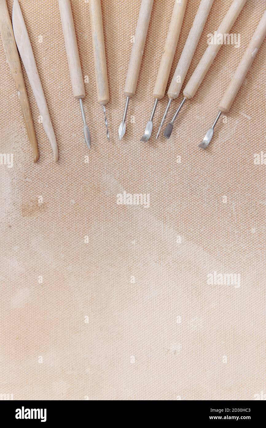 Metal spatulas for decoration of clay products lie on a rough cloth ...
