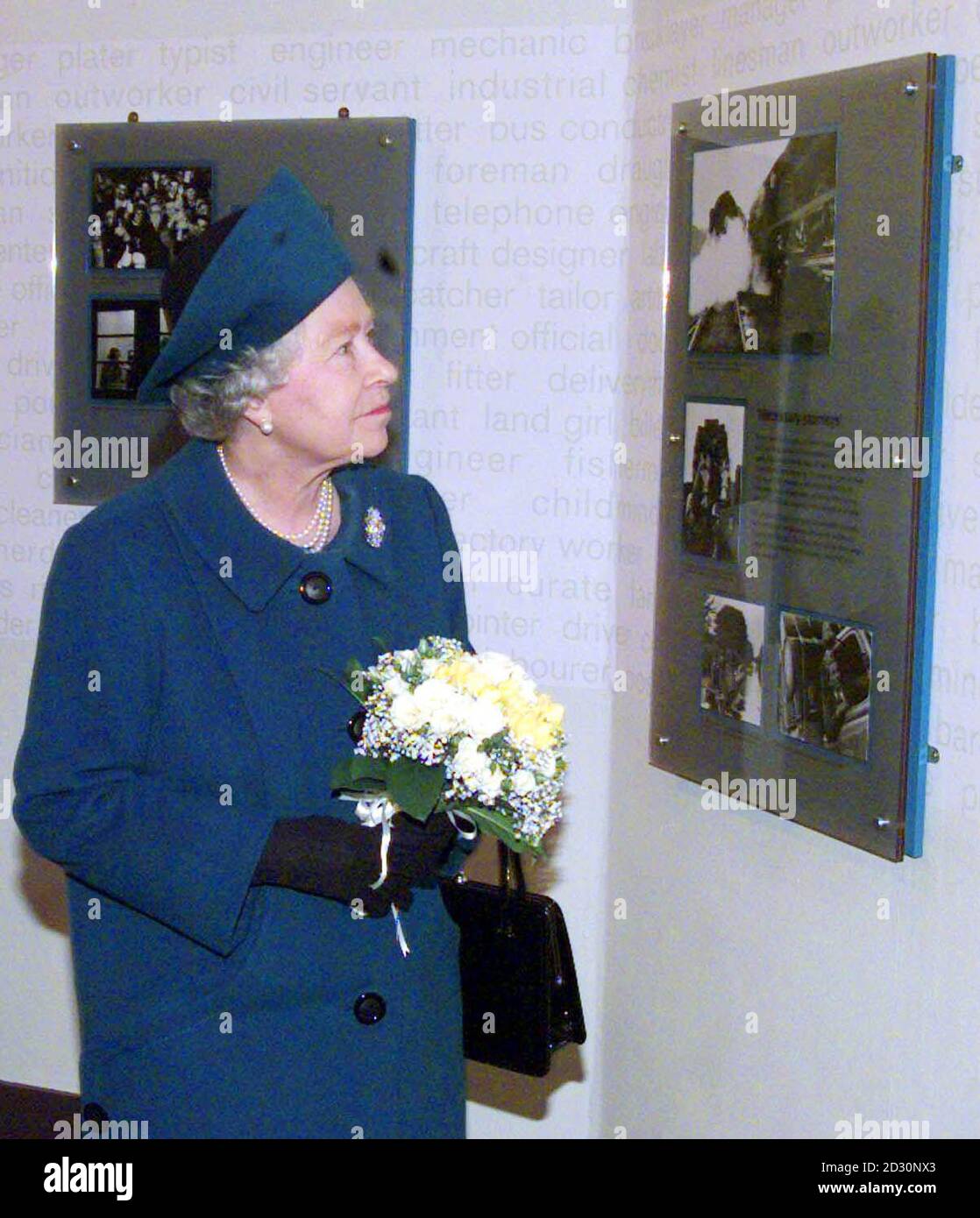 The Queen looks at photographs during a visit to the the Imperial War ...