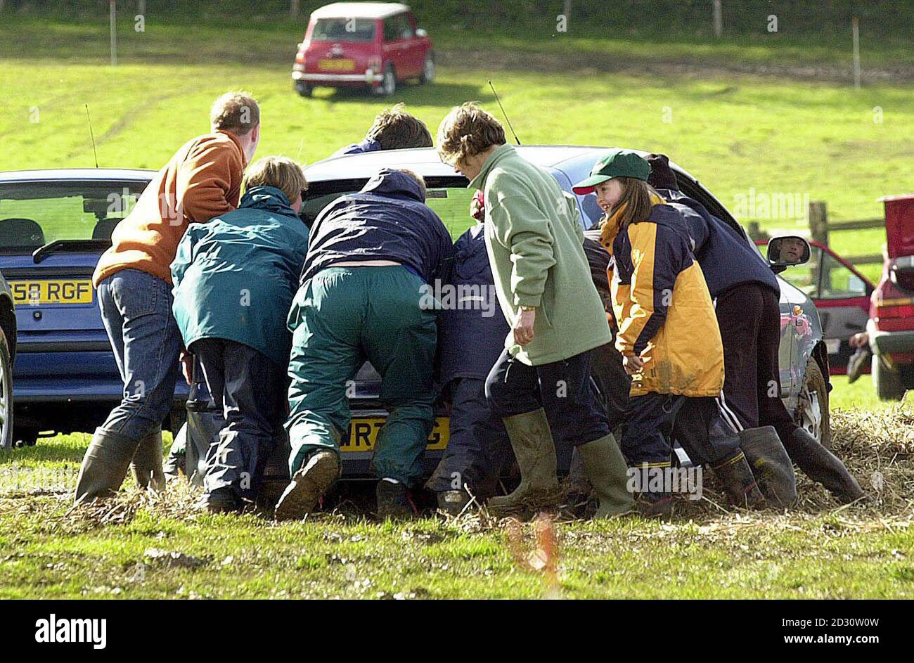 Race-goers push a car out of the mud in the car park, as they prepare ...