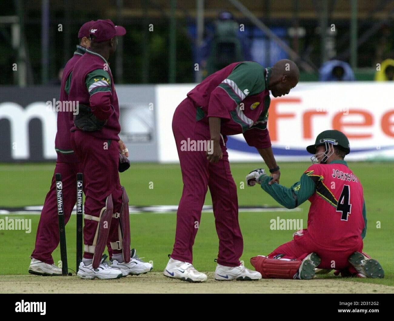 Zimbabwe's Neil Johnson is helped off the ground by bowler Franklyn ...