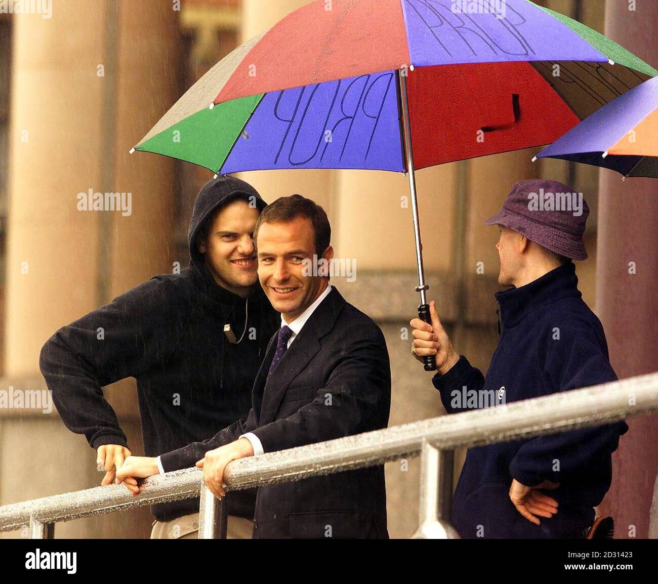 Actor Robson Green (centre) shelters from the rain during filming of ...