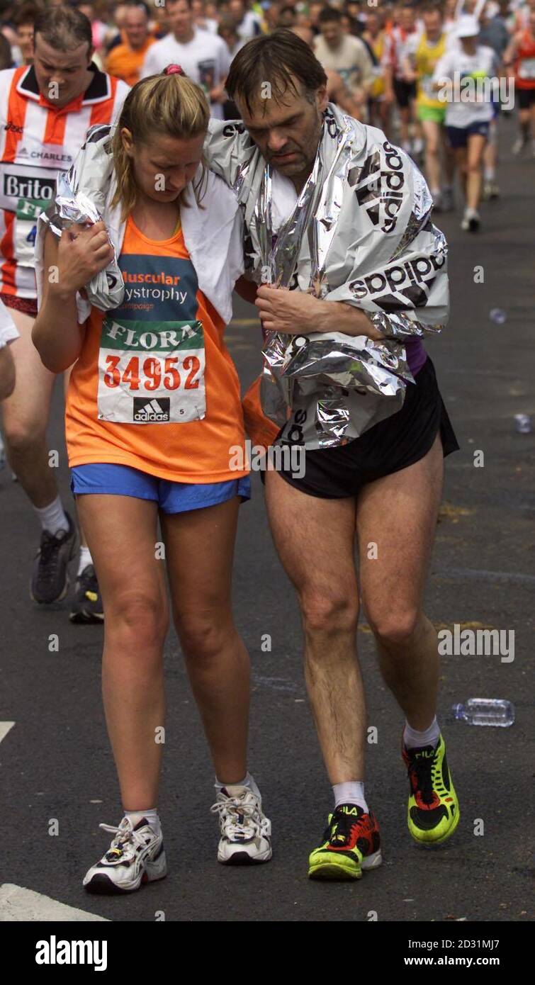 Two exhausted runners help each other along The Embankment towards the ...