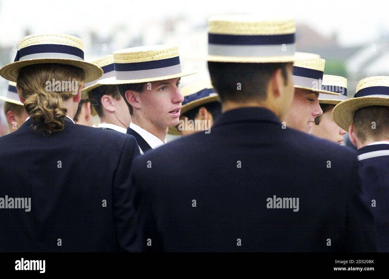 Young men wearing boaters watch the boats at the racing event at Henley ...