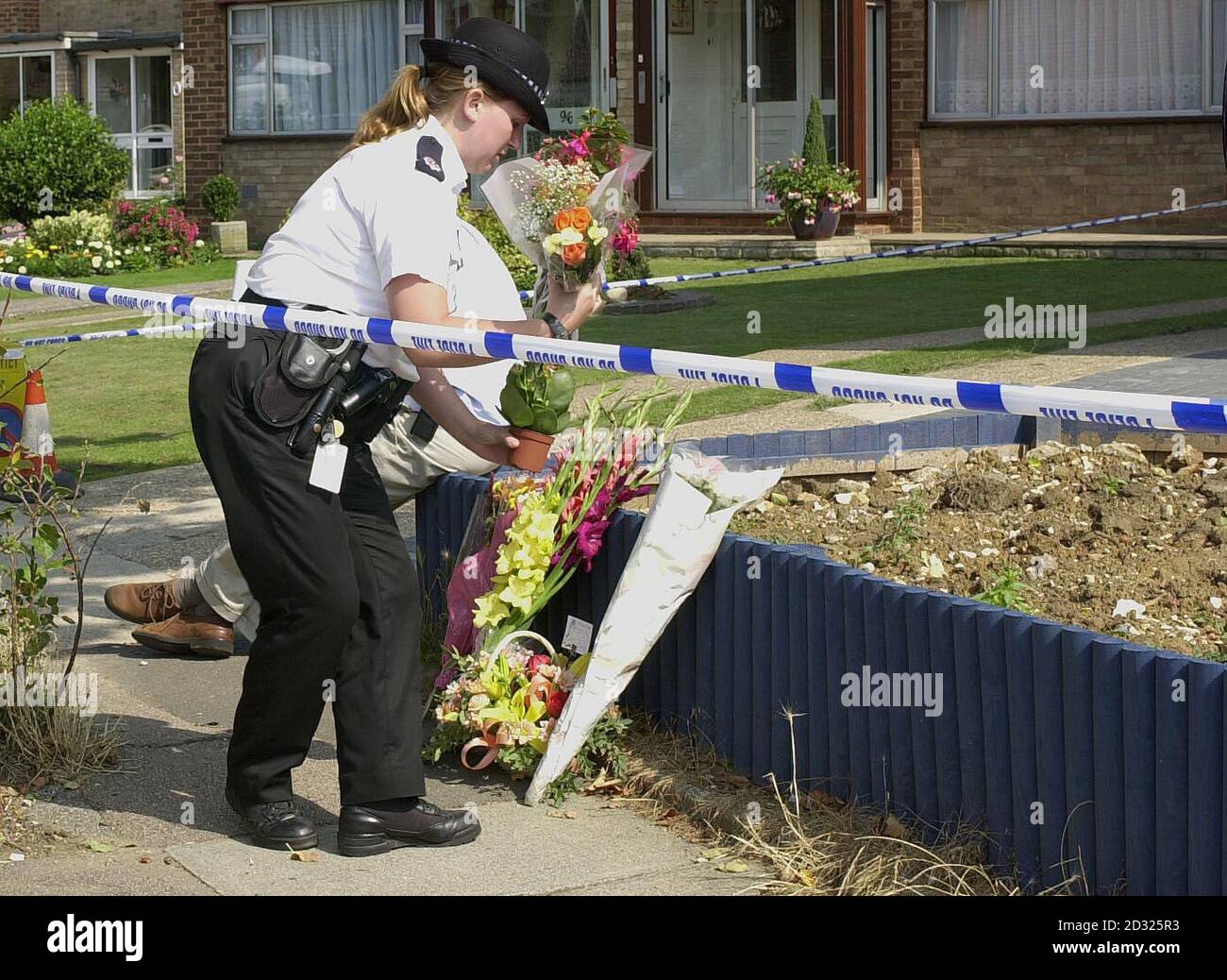 A police woman lays flowers from neighbours outside the home of Kent ...