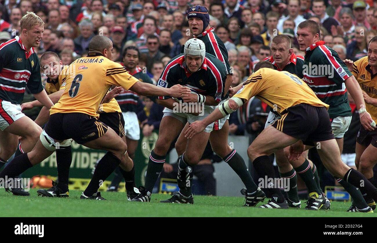 Leicester's Will Johnson breaks through the tackles of Gavin Thomas ...
