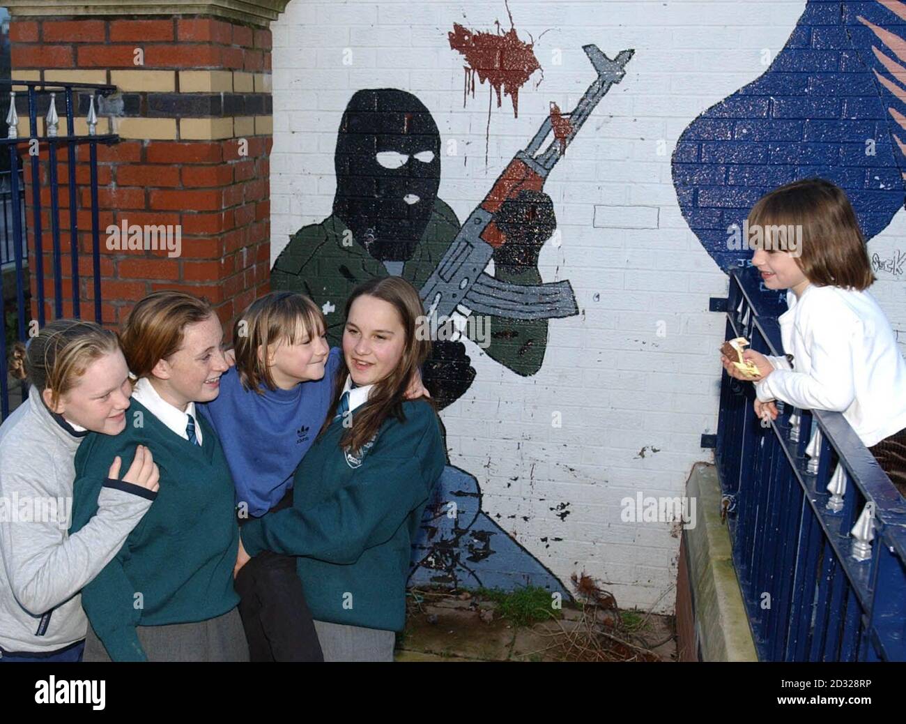 Schoolgirls play in front of an IRA Mural in the Nationalist Markets ...
