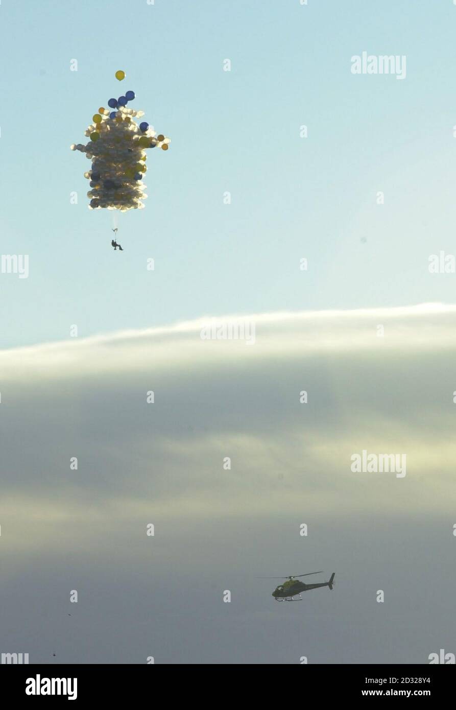 Balloon pilot Ian Ashpole sits in a harness attached to six hundred toy ...