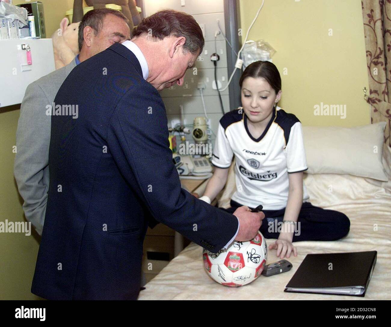 The Prince of Wales signs a football for patient Emma Ward in a ward ...