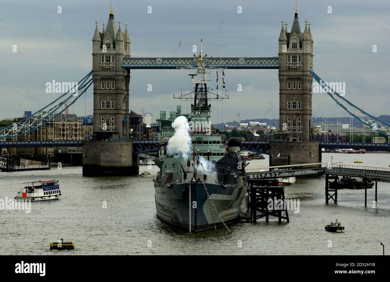 HMS Belfast, moored between London Bridge and Tower Bridge, fires a ...