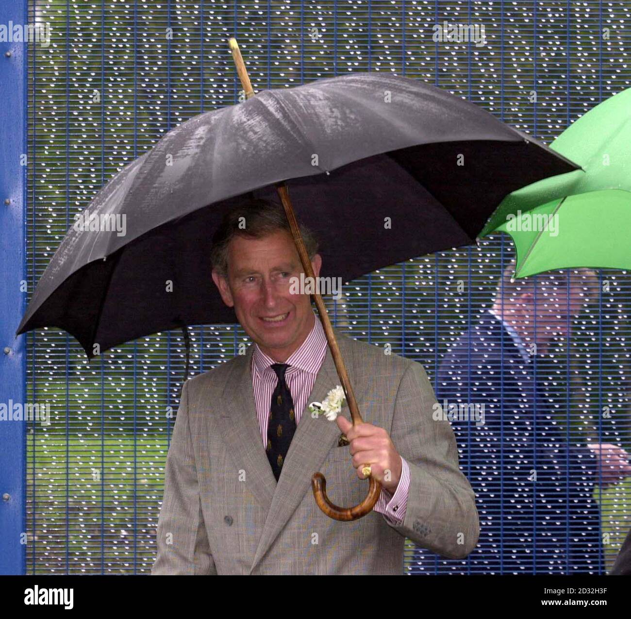 The Prince of Wales shelters under an umbrella during his visit to ...