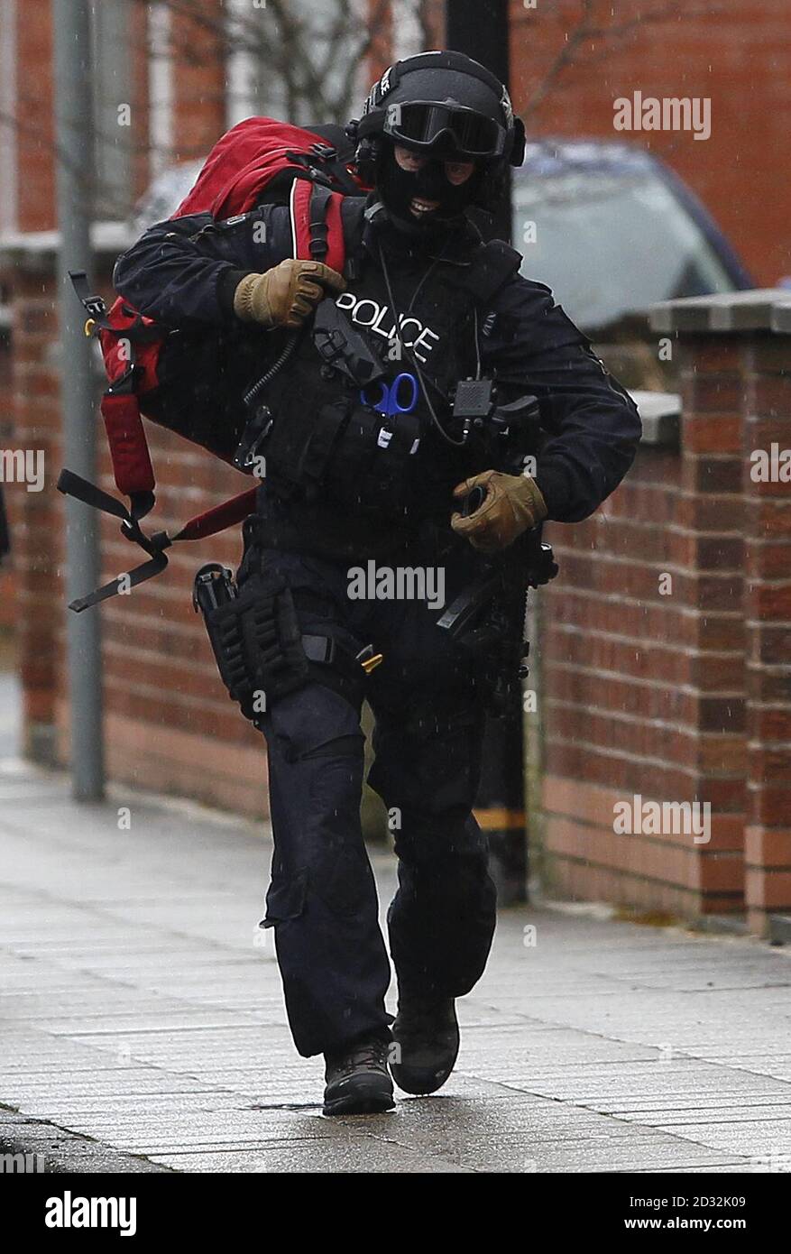 An armed police officer leaves a property in the Trafford area of ...